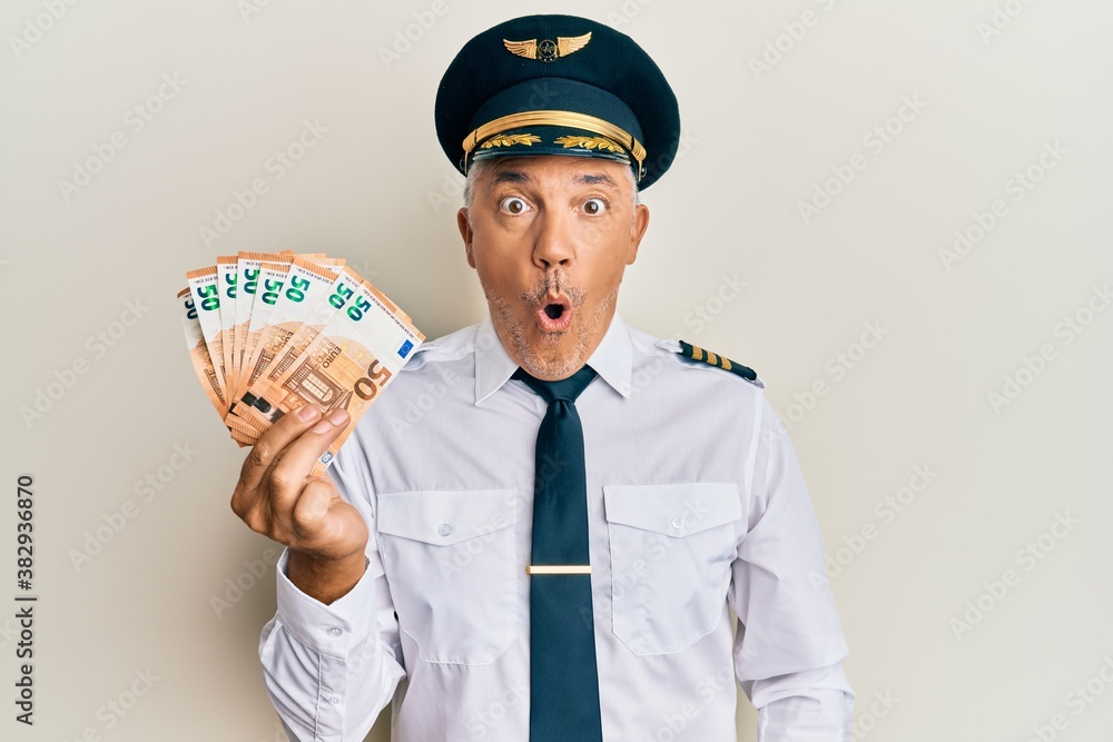 Handsome middle age mature man wearing airplane pilot uniform holding ...