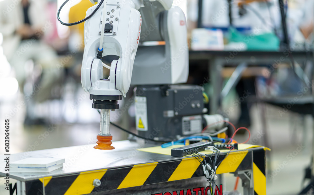 Man is holding a teach pendant to control a robot arm that is ...