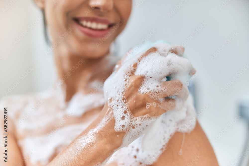 Cheerful young woman washing her body with bath loofah Stock Photo ...