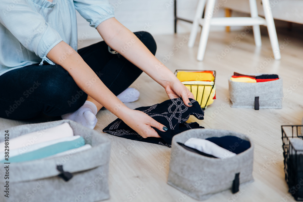 Woman folding clothes on the floor, organizing stuff in baskets and ...