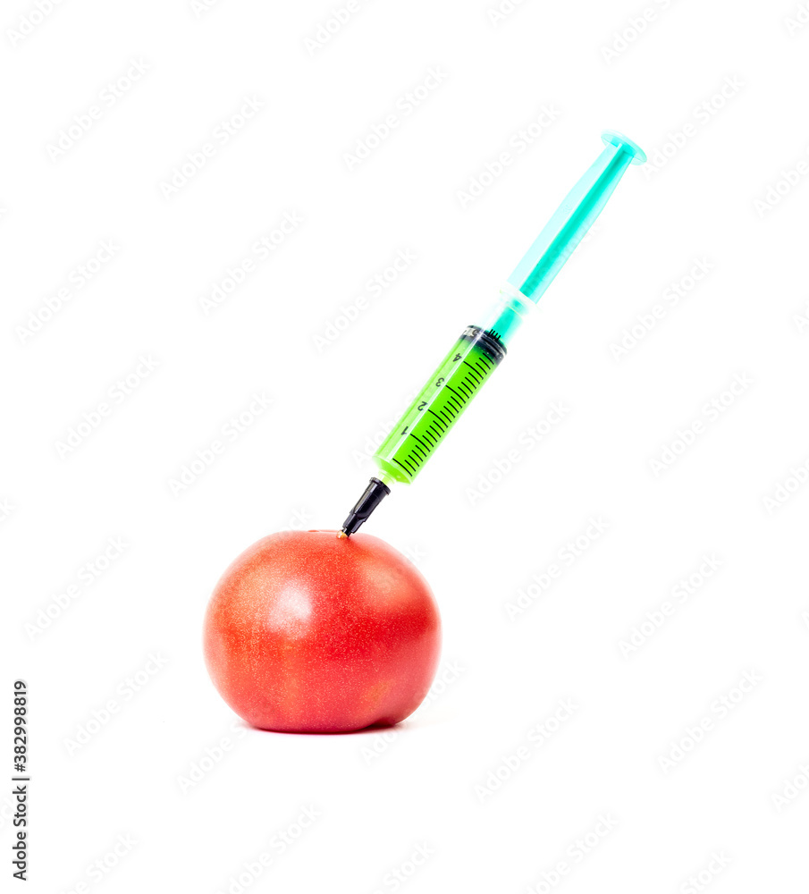 Injection of a medical syringe with liquid stuck in a fresh tomato ...