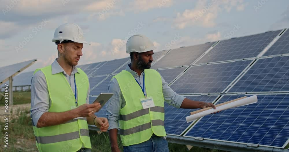 Male engineers with tablet and scrolls of engineering drawing ...