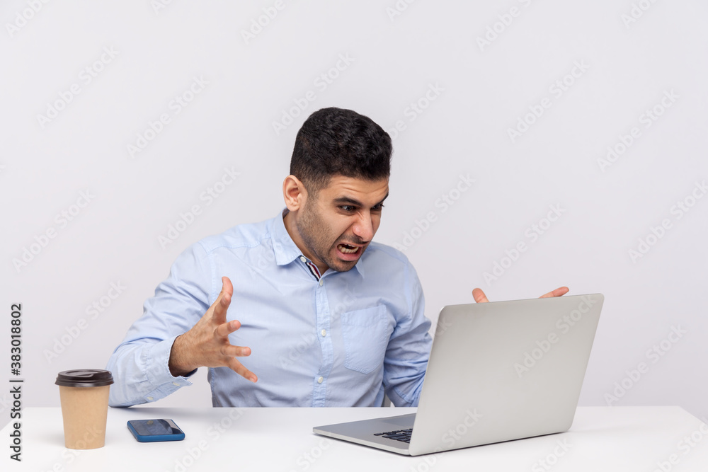 Irritated businessman sitting office workplace, looking at laptop with ...