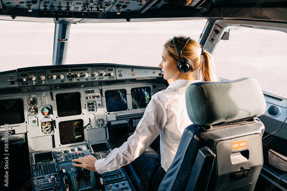 Woman pilot flying an aircraft, sitting in cockpit, wearing headset ...