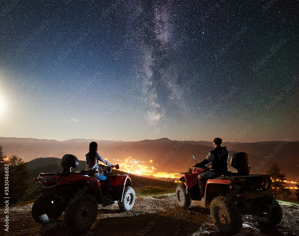 Back view of man and girl trevelers riding on atv quad motorbikes on ...
