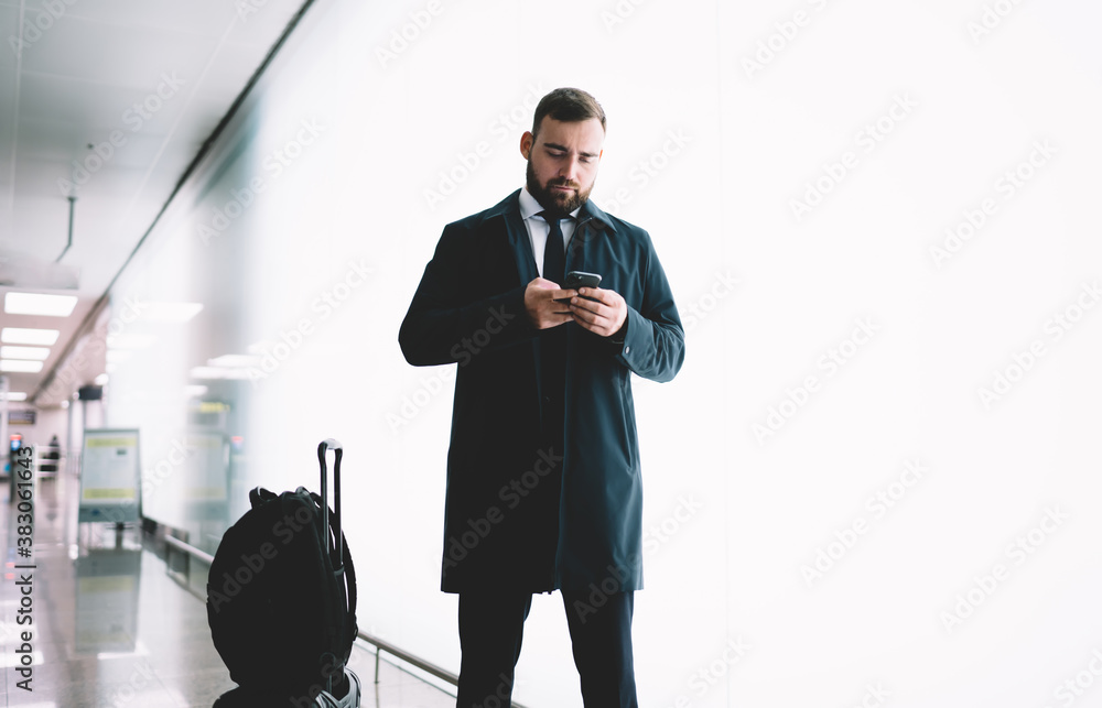 Caucasian businessman with suitcase baggage messaging via smartphone ...