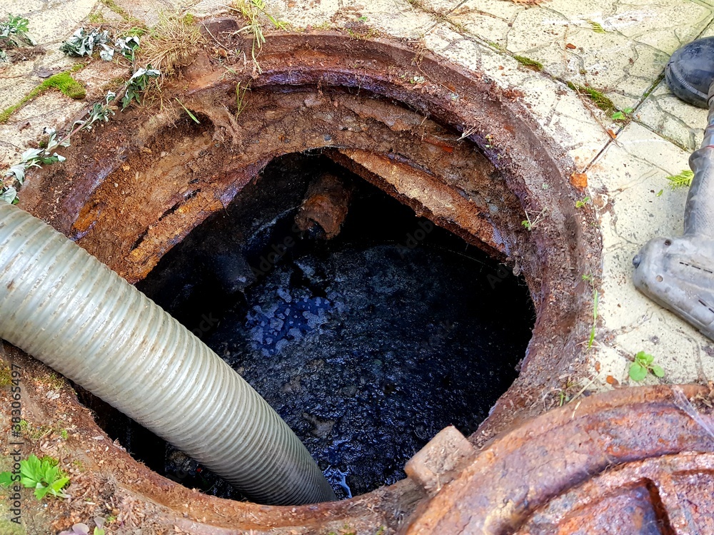 A hose is lowered into the sewer manhole to pump water out of the pit ...