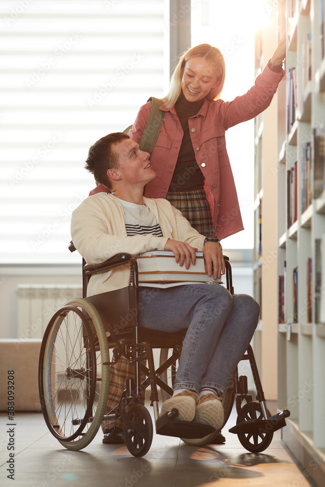 Vertical full length portrait of young man using wheelchair in school ...