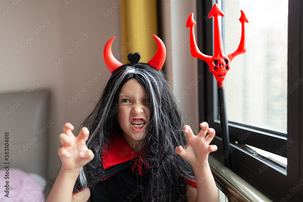 Little Girl in costume of devil with red horns at home. Happy Halloween ...