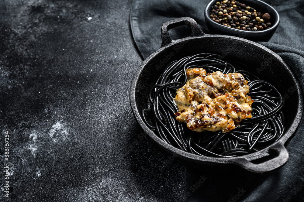 Black spaghetti pasta with squid ink in a pan. Beef in pepper sauce ...