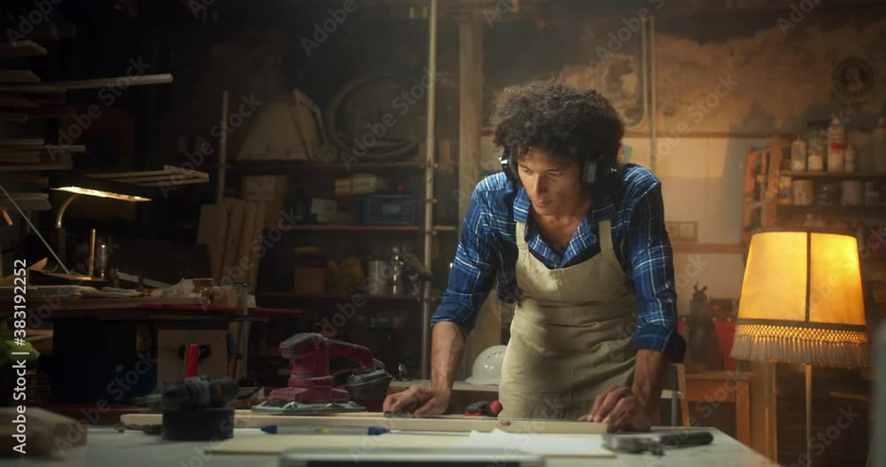 Attractive concentrated Latin male carpenter creating wooden furniture ...