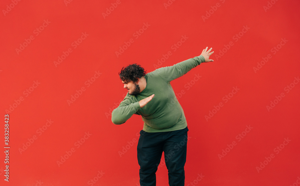 Positive fat man in casual clothes and curly hair dances a dub dance on ...