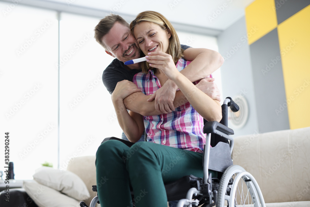Husband hugs his wife in wheelchair by shoulders with positive ...