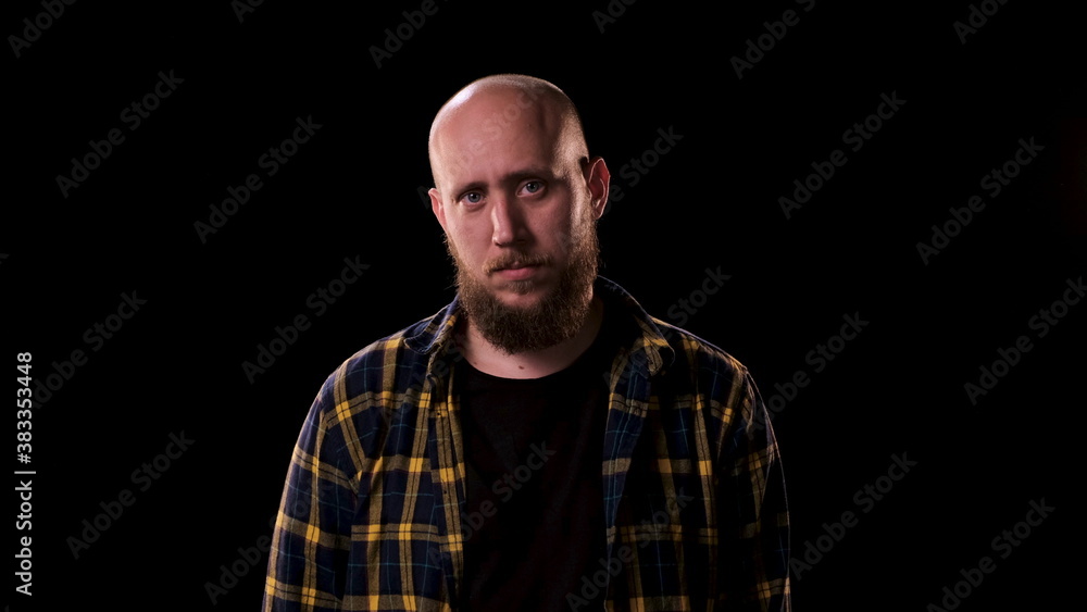 Bald bearded man in checkered shirt looks intently and angrily at the ...