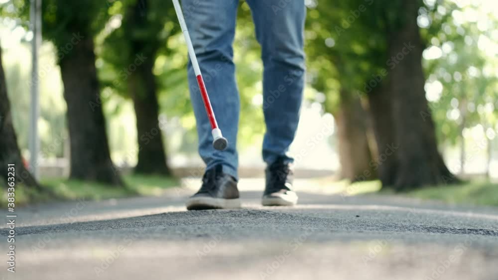 Blind man walking in park, using long cane to scan way for obstacle ...