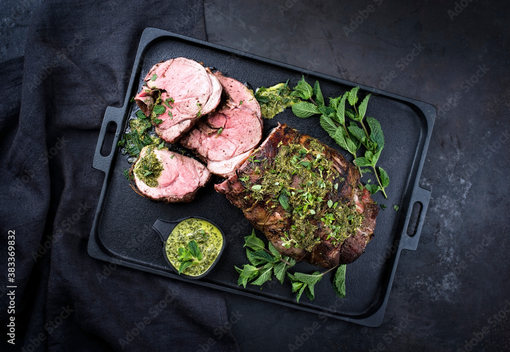 Traditional English barbecue lamb roast sliced with mint leaf and sauce ...