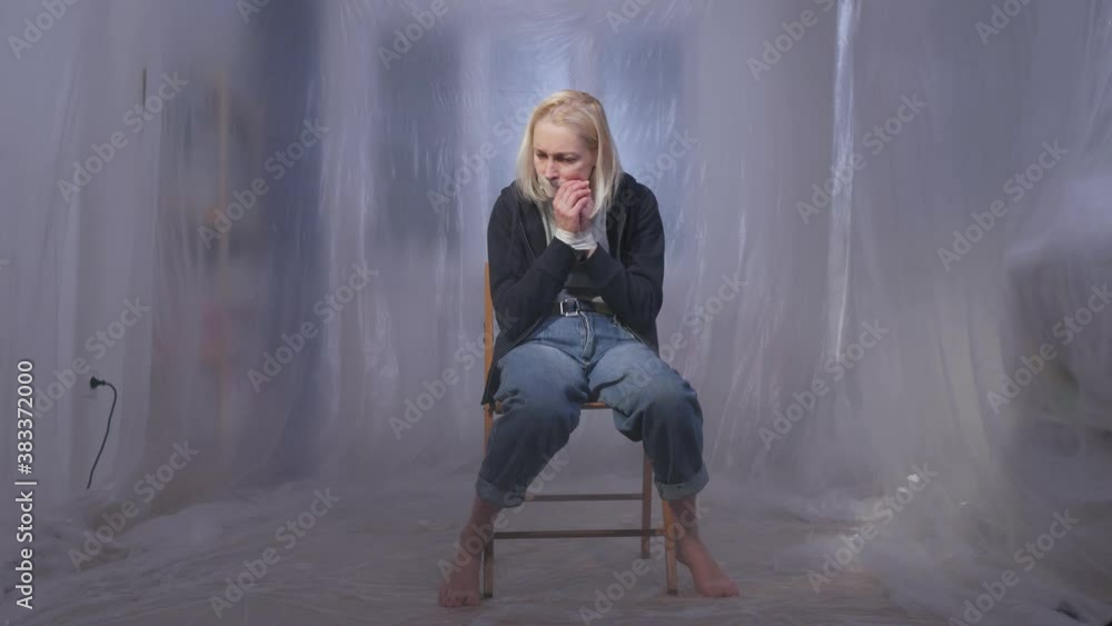 Female hostage sitting on a chair in a room with her mouth taped shut ...