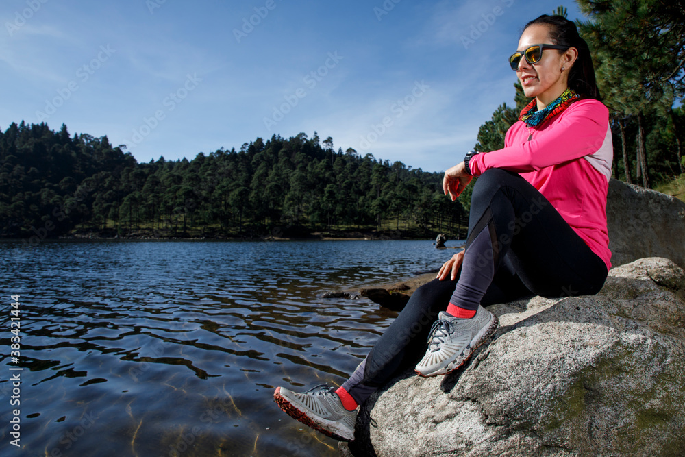 Atleta descansando a la orilla de un lago sentada sobre una piedra ...