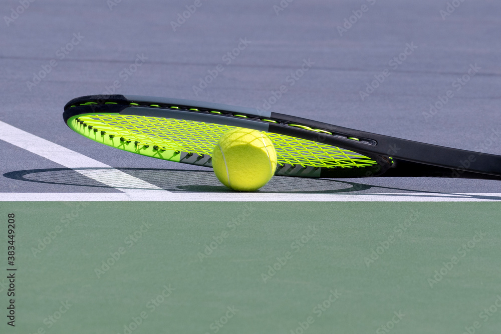 Tennis racket on ball on hard tennis court. Bicolor - green and purple ...