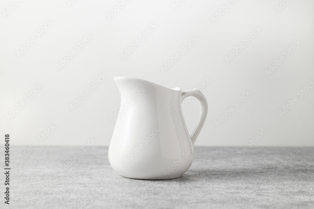beautiful vintage milk jug of white color on a light concrete ...