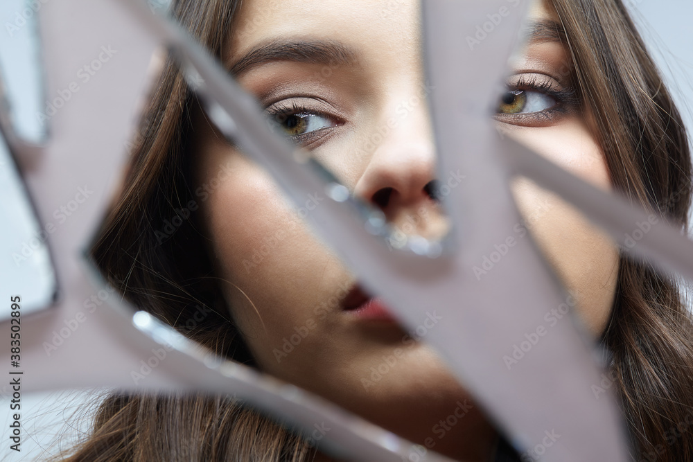 Young woman looks in a broken mirror. Portrait of beautiful female in ...