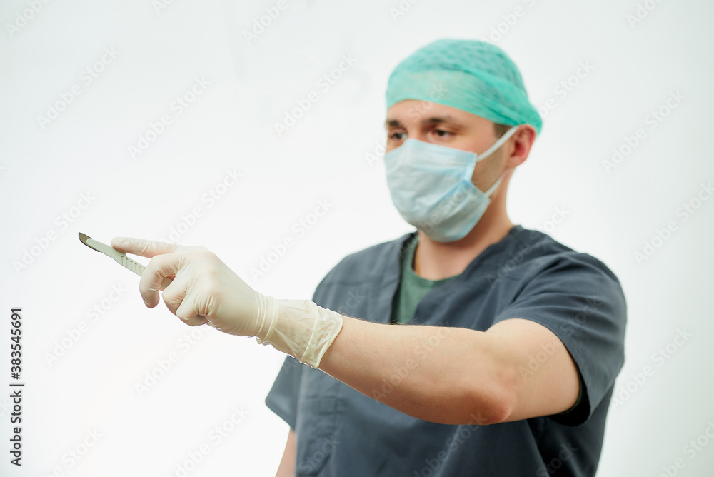 A side view of a male surgeon in scrubs with a focus on a scalpel in a ...