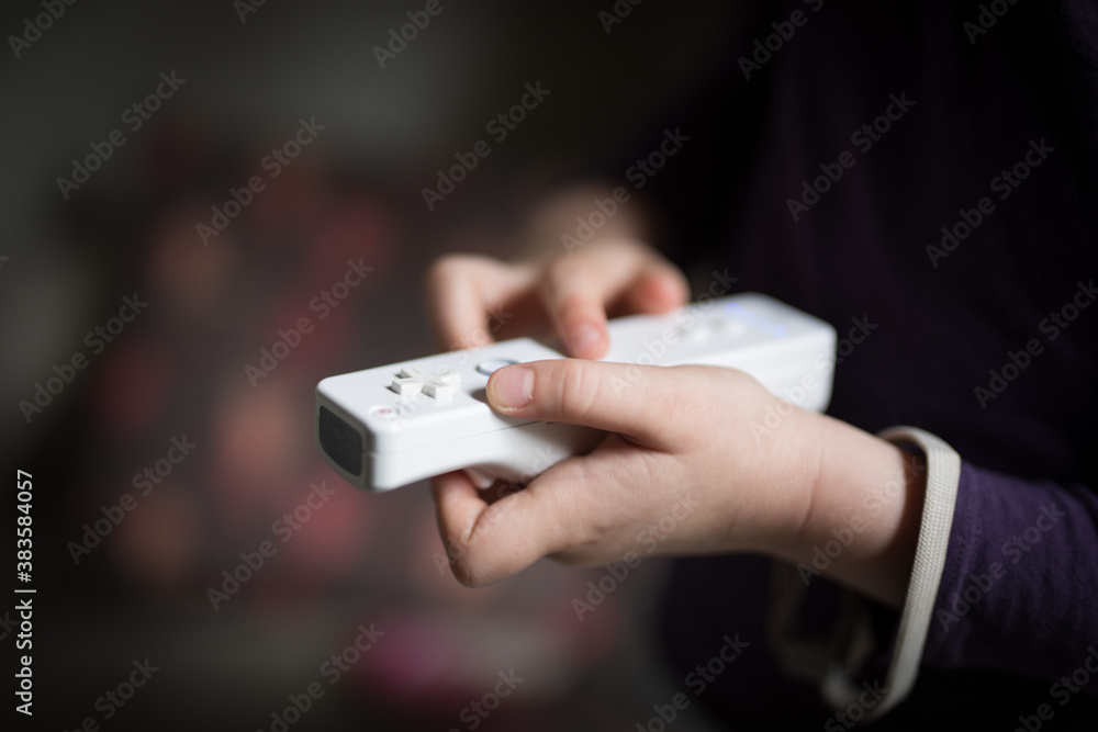 A small child girl dressed in pink holding a gaming consolte controller ...