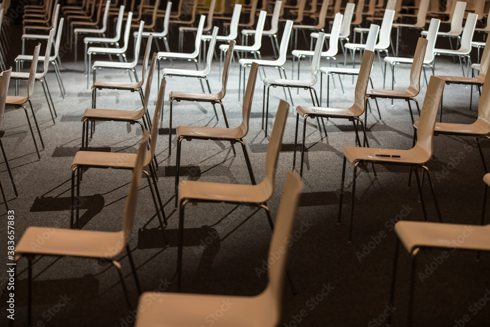 Group of socially distanced empty white chairs arranged for indoor ...