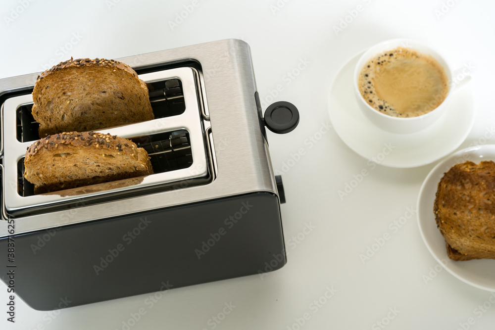 Toaster with multi-grain bread and a cup of black coffee on white ...
