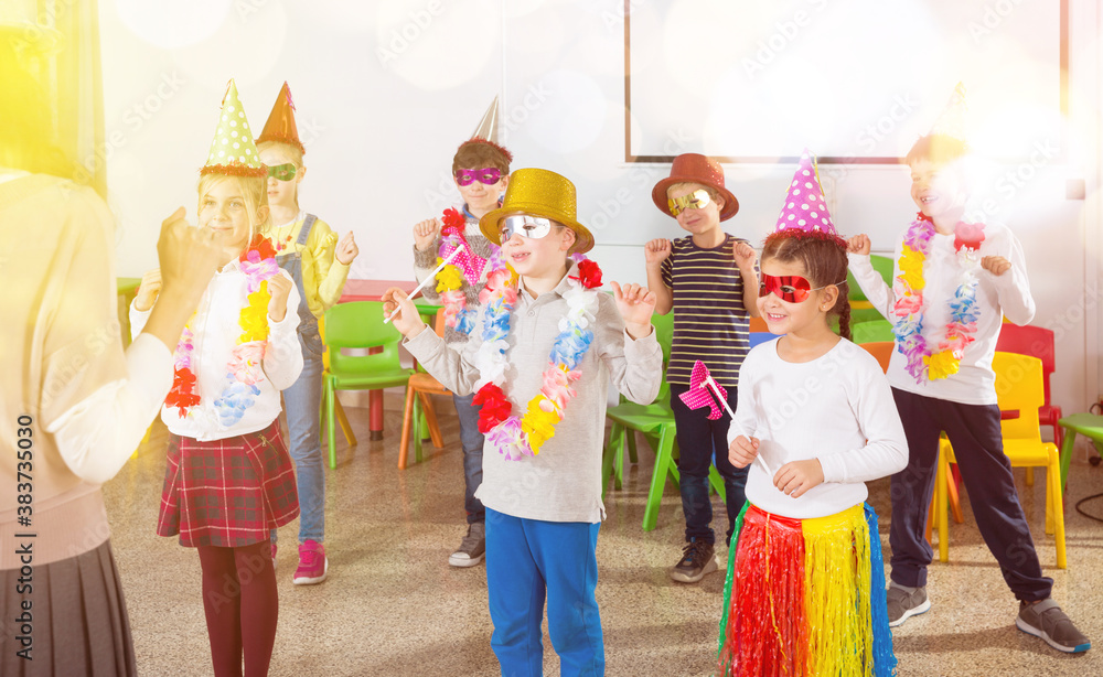 Group of cheerful school kids wearing festive hats having fun with ...