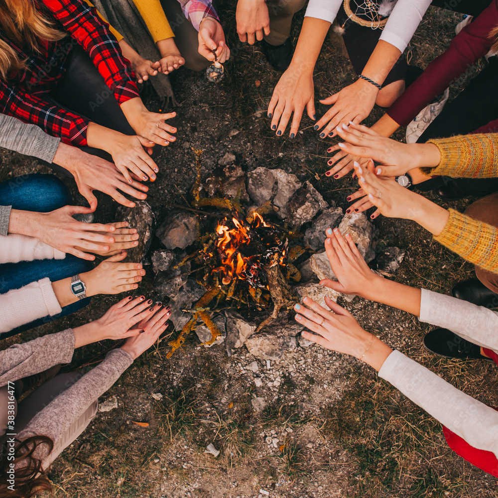 Top view of young campers sitting around and warming their hands on a ...