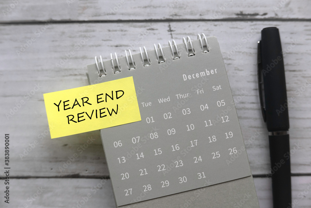 Top view of pen ,calendar and sticky note written with Year End Review ...