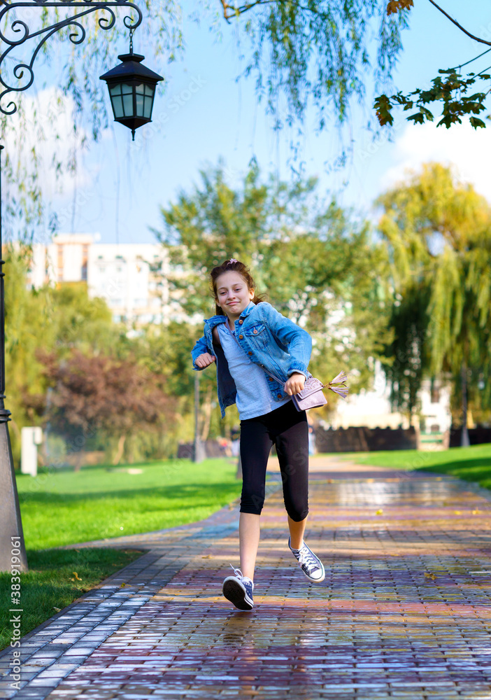 girl runs through sprinkled water in a city park, bright summer day ...