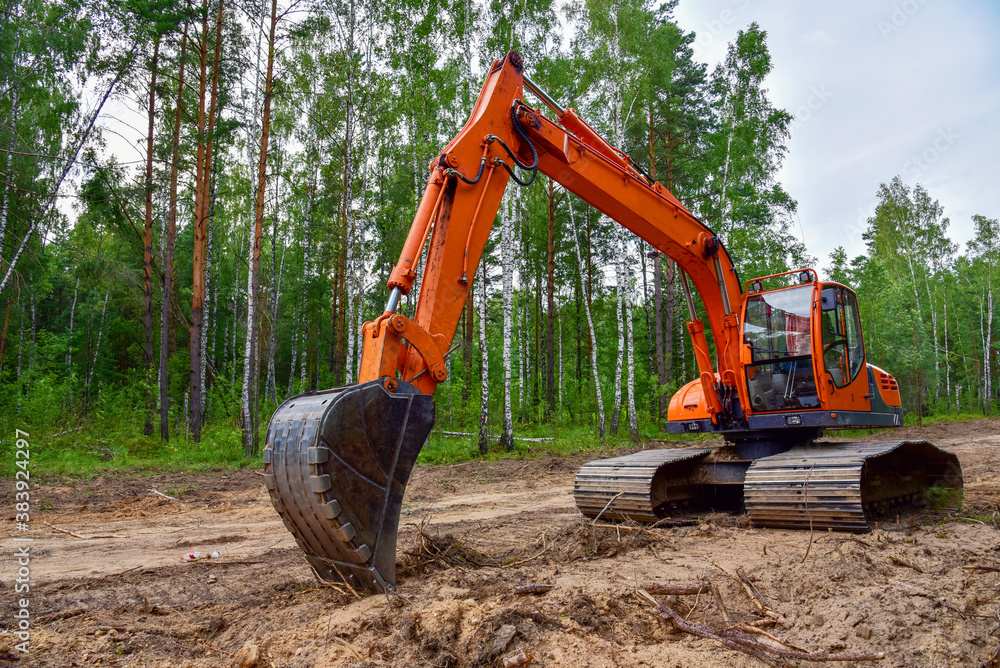 Excavator clearing forest for new development. Orange Backhoe modified ...