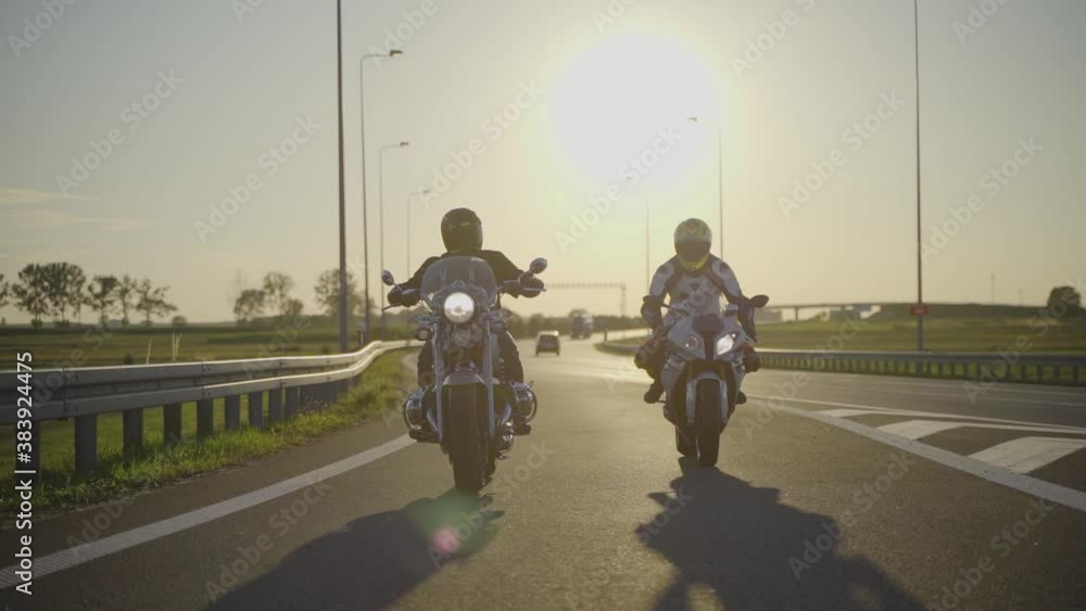 Two motorcyclists riding different type of motorcycles fist bumping ...