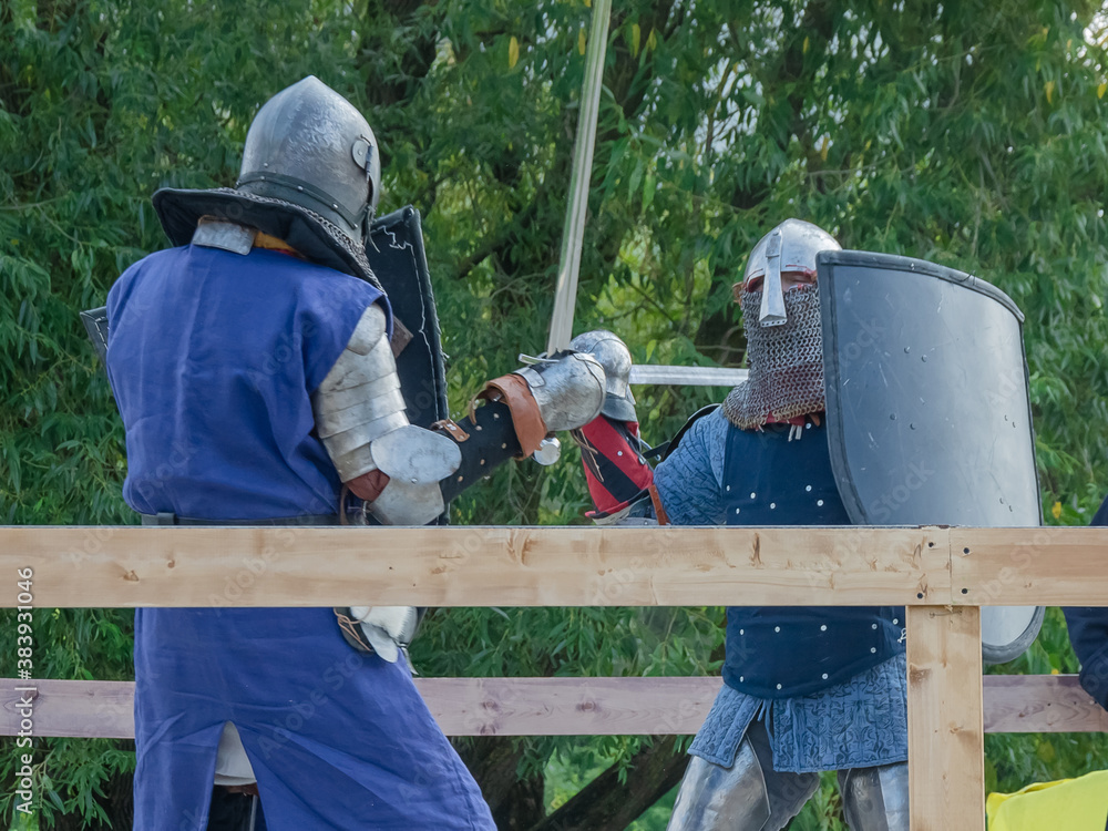 Foto de Two knights on foot in heavy medieval armor fight with swords ...