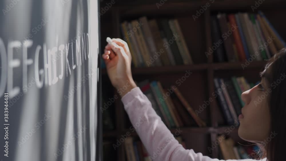 Indian kid primary school girl pupil holding chalk writing alphabet ...
