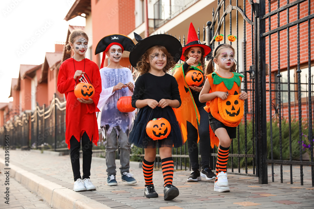 Cute little kids wearing Halloween costumes going trick-or-treating ...