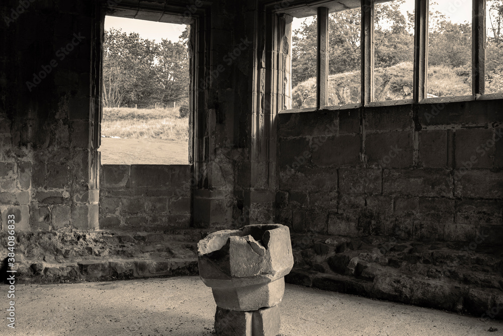Chapter house interior of a medieval abbey, with a stone font. With ...