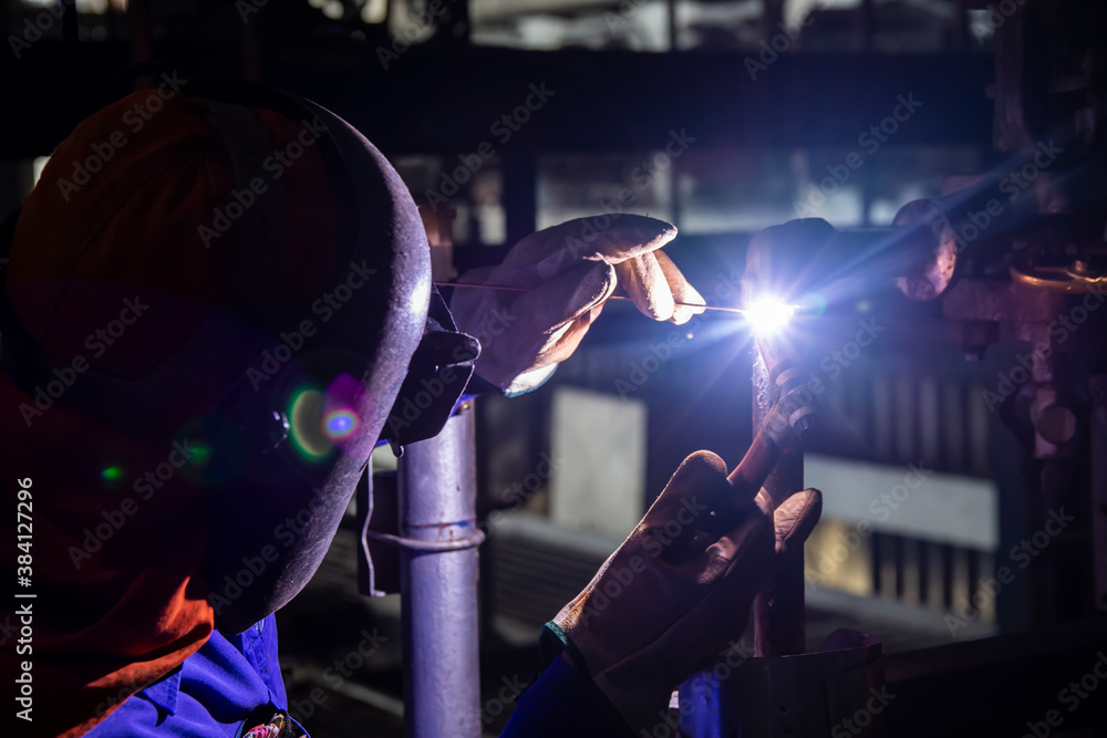 Welder is assembling the workpiece by process shielded metal arc ...