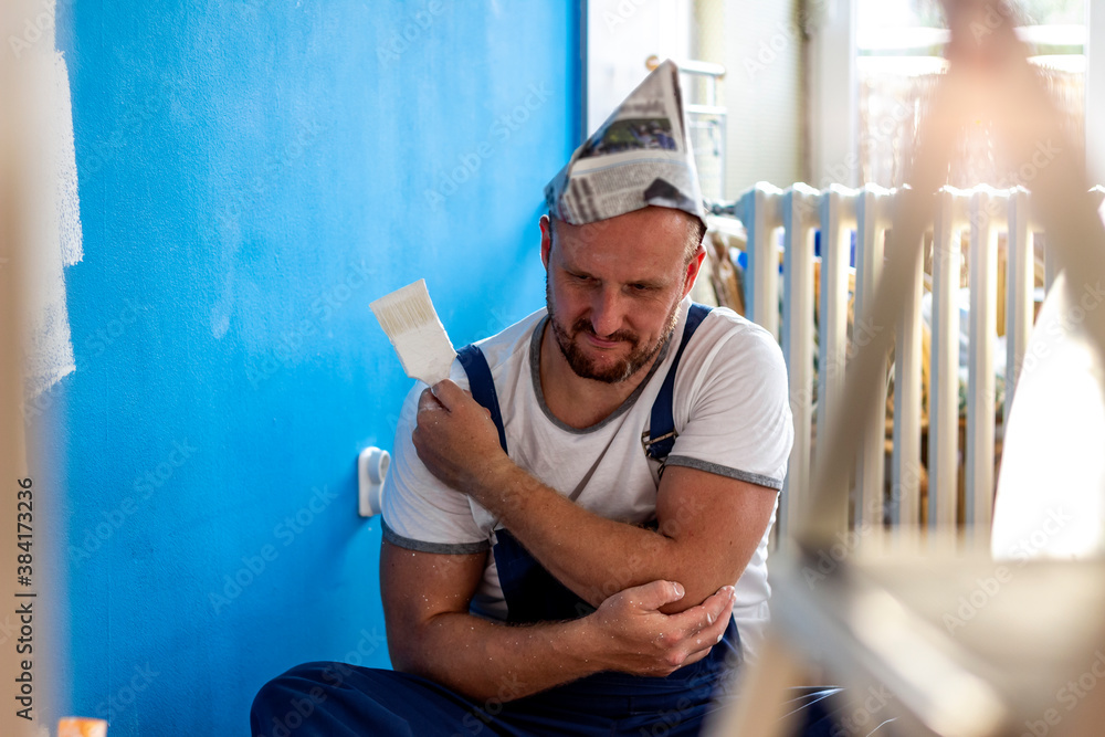 Shot of exhausted painter suffering from pain in his shoulder after ...