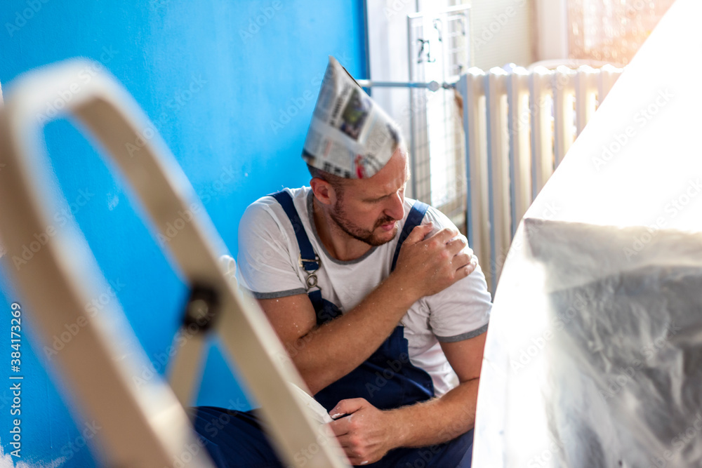 Shot of exhausted painter suffering from pain in his shoulder after ...