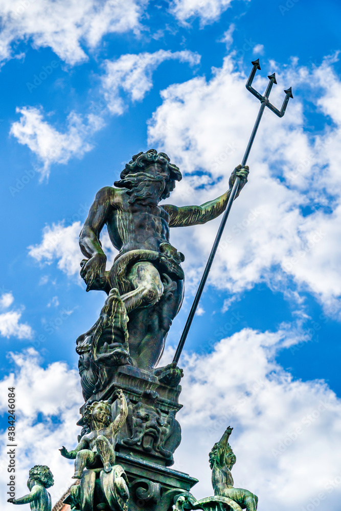 The statue of Neptune with trident on a blue sky with white clouds ...