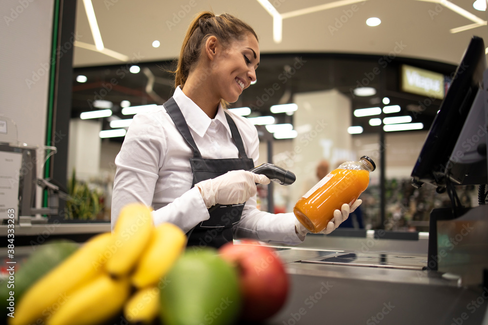 Portrait of female cashier in supermarket scanning bar code of products ...
