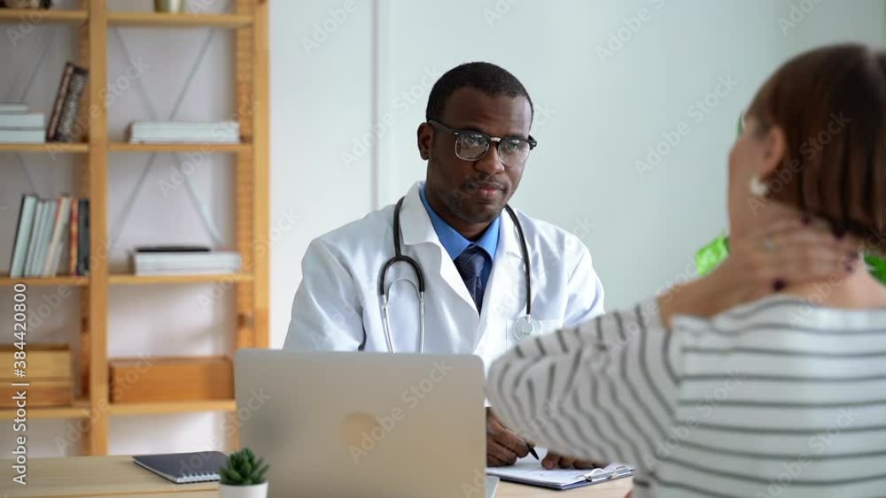 Young male african doctor talking to patient about disease during ...