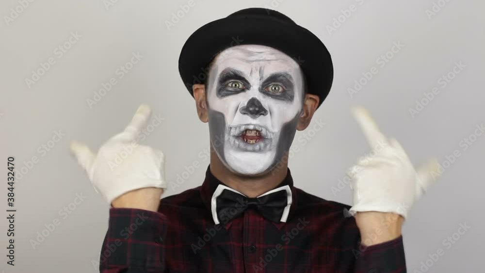 A terrible man in clown makeup, shows an indecent gesture. The scary ...