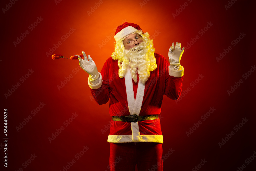 Male actor in a costume of Santa Claus holds red fur handcuffs and a ...