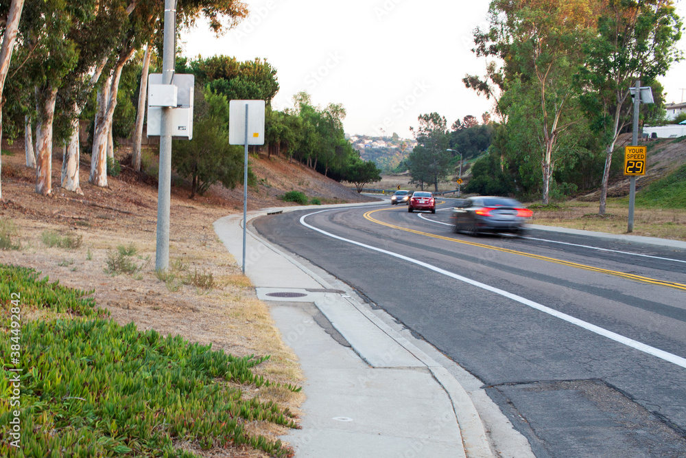 Radar speed indicator sign and cars on the on the wavy road at day time ...