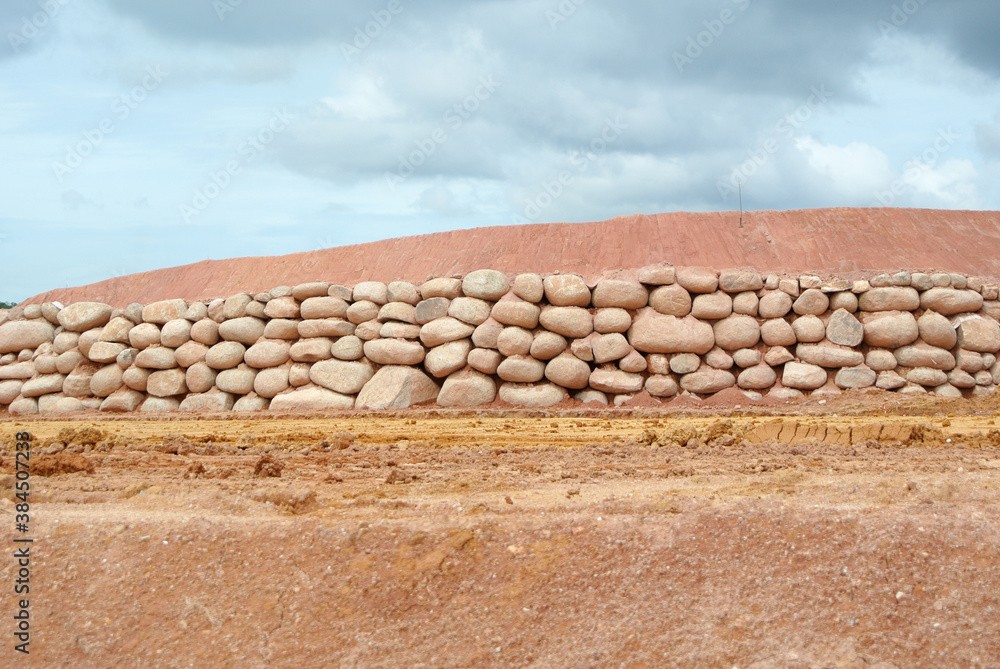 Stone boulders are stacked on the ground and used as retaining walls ...
