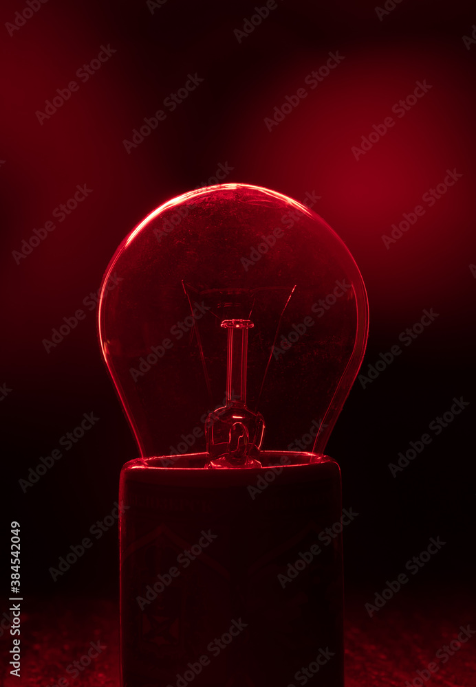 Incandescent light bulb in red light, bulb contour. Incandescent light ...